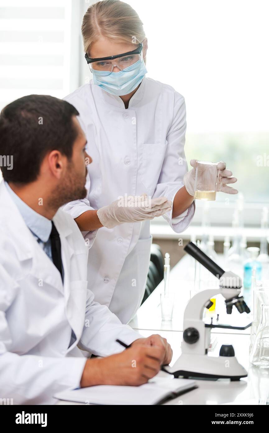 This is what we are testing today. Side view of two scientists making ...