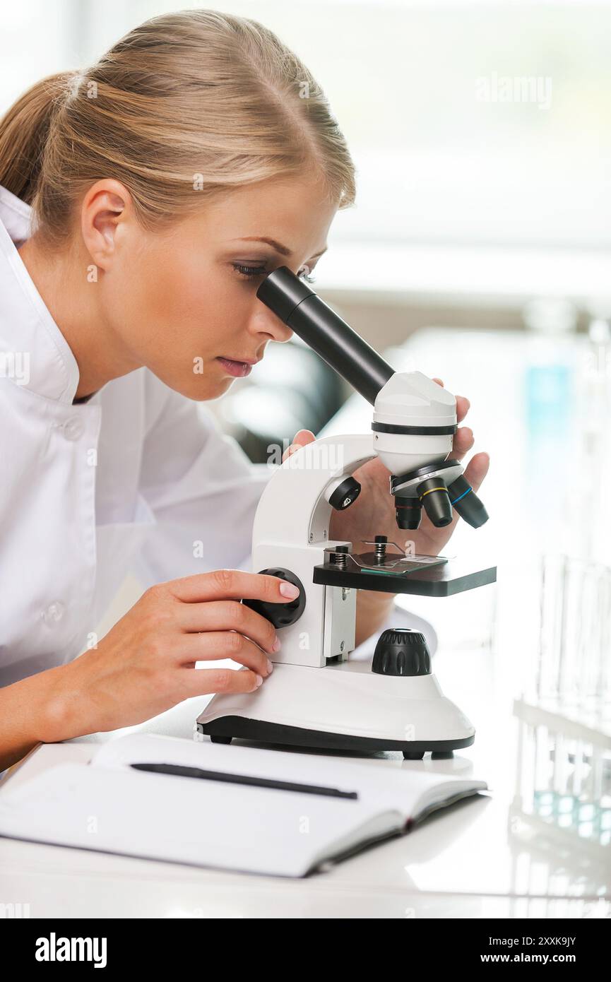 Scientist at work. Side view of confident young female scientist using ...