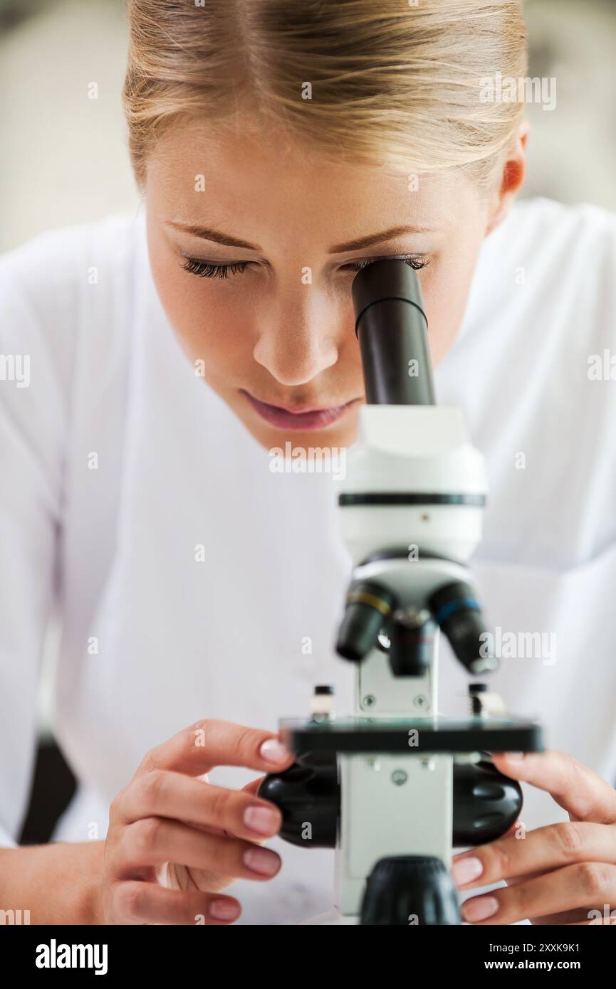 Taking closer look. Concentrated young female scientist using ...