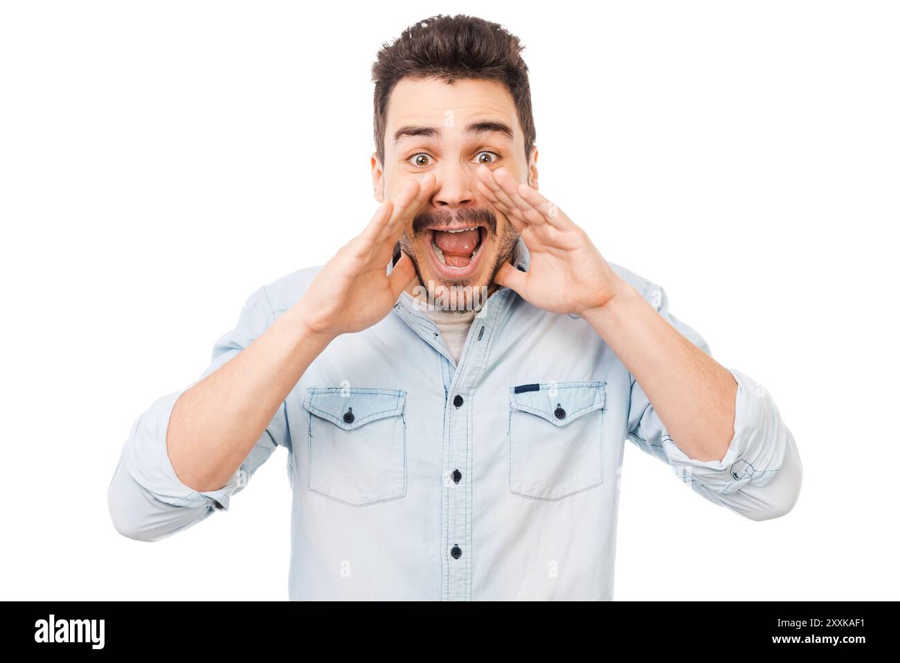 Great news! Cheerful young man in holding hands near mouth and shouting ...