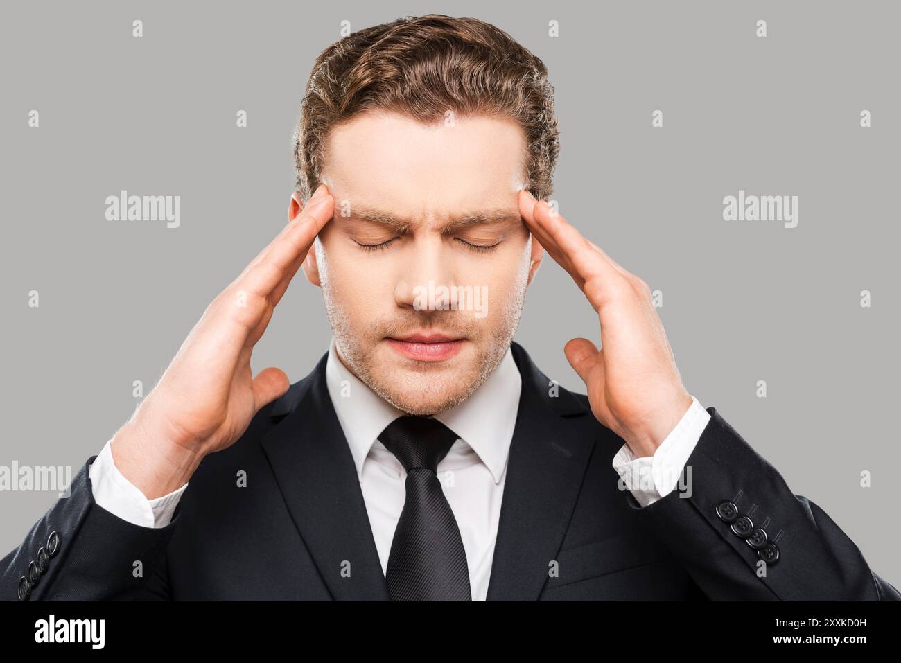Too much stress. Frustrated young man in formalwear touching head with fingers and keeping eyes ...