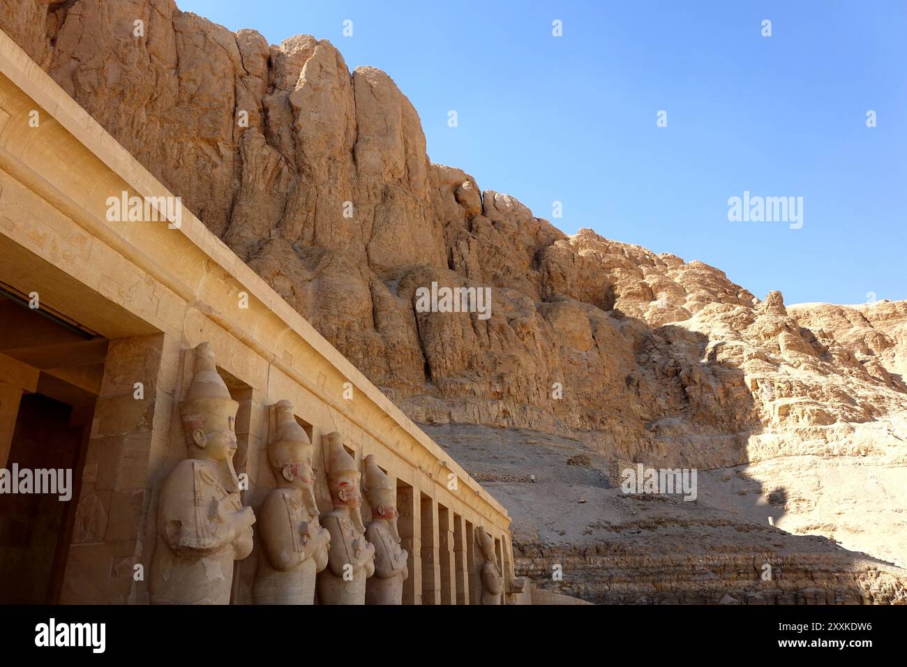 The ancient statues line the entrance of Hatshepsut's mortuary temple, surrounded by the rugged ...