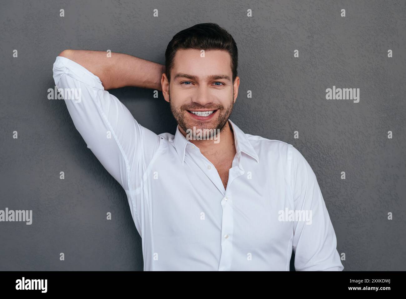 Charming handsome. Handsome young man holding hand behind head and ...