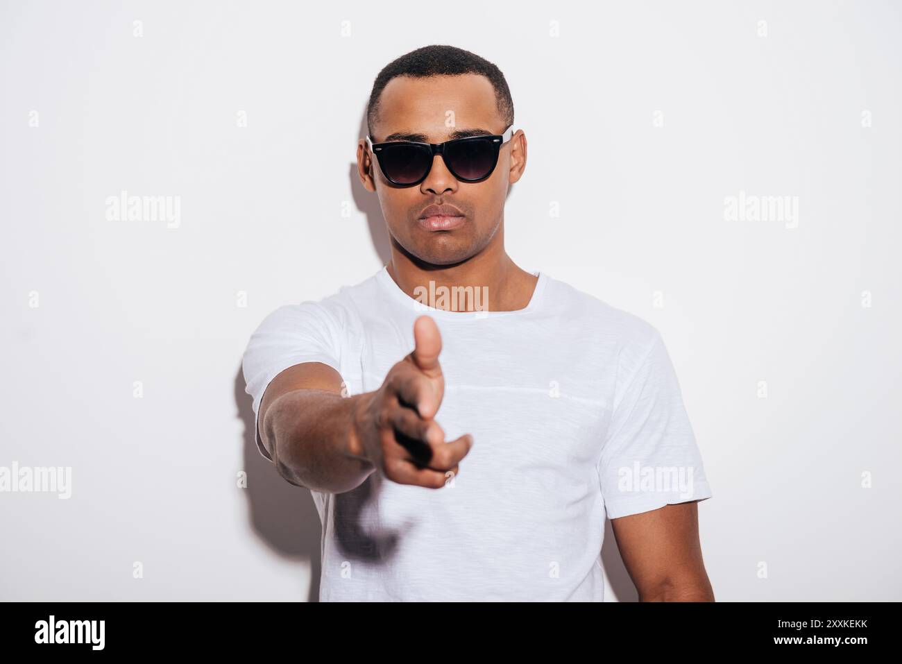 Hands up! Serious young African man in sunglasses gesturing finger gun ...