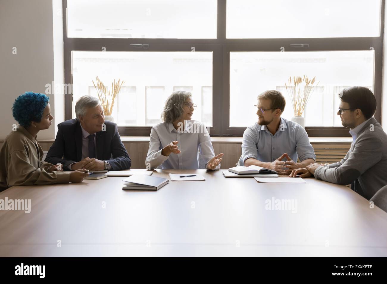 Five multiethnic staff members engaged in briefing at conference table ...