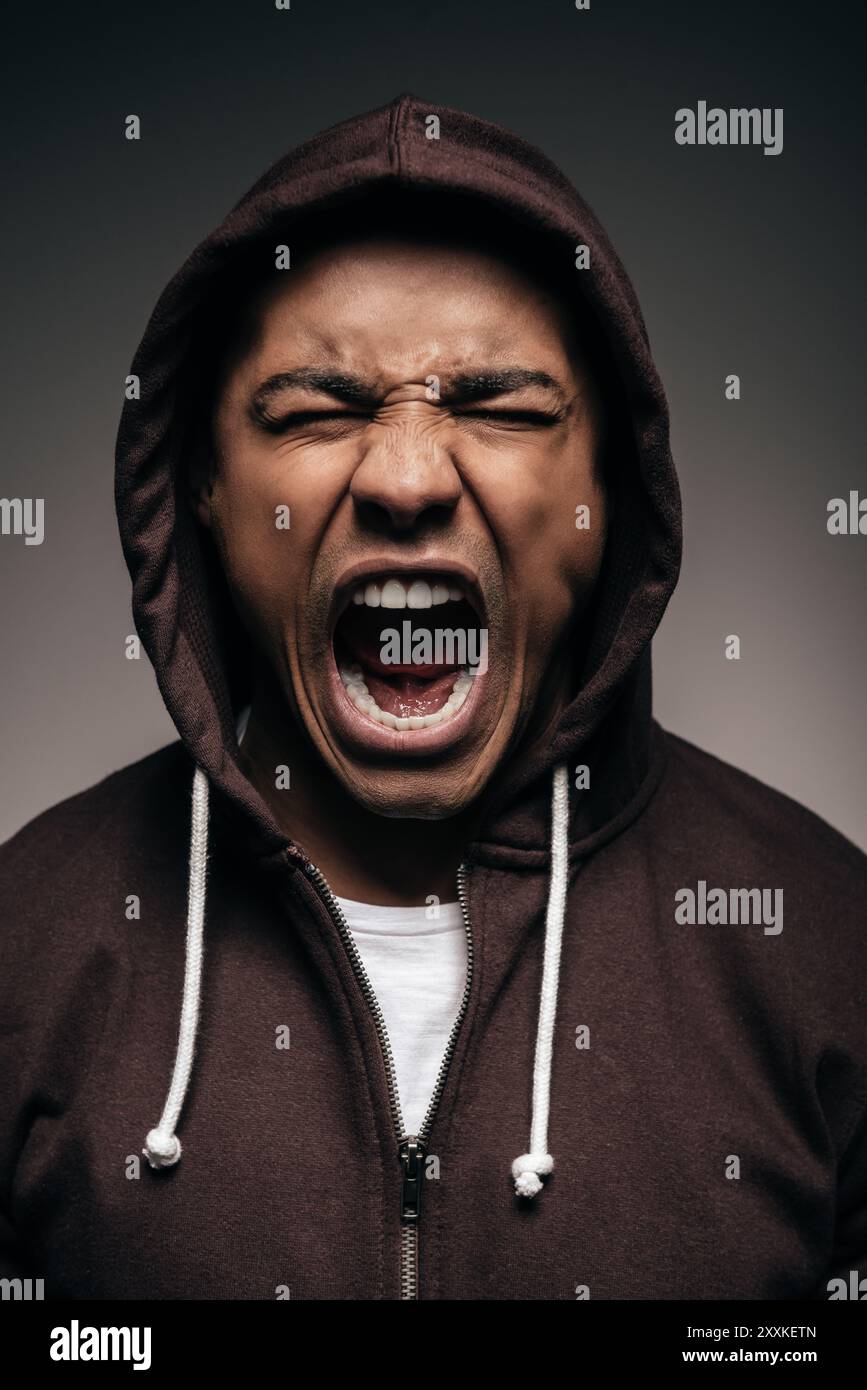 Energy inside him. Furious young African man in hooded shirt keeping ...