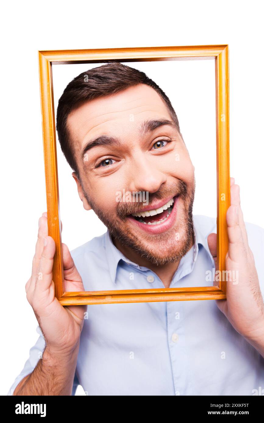Joyful frame. Handsome young man in shirt holding picture frame in ...