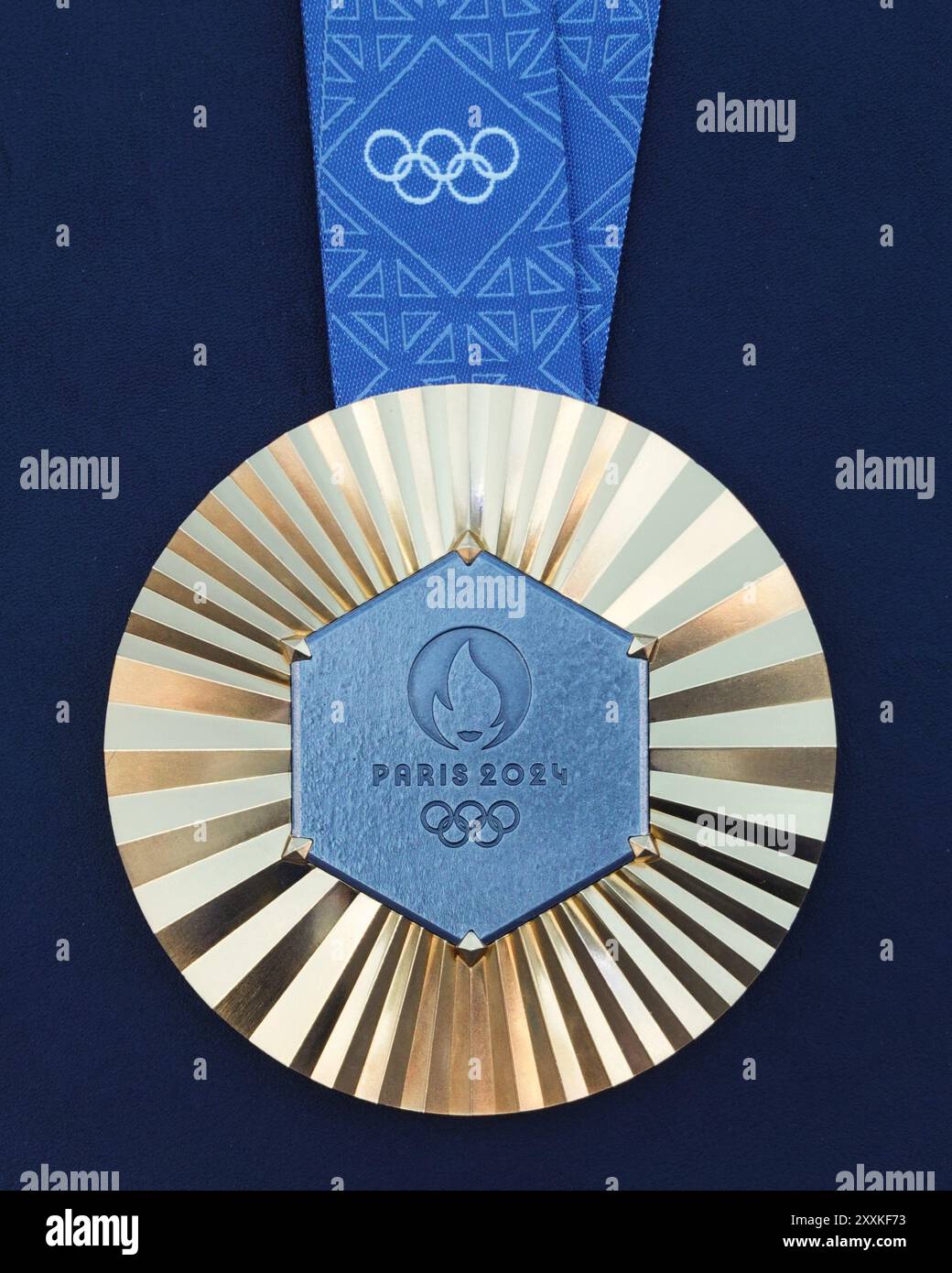 A Paris 2024 Olympic gold medal on display showing a piece of the ...