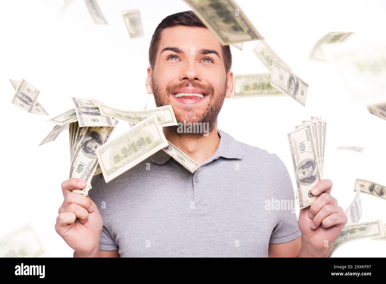 Money from the sky. Happy young man looking up and holding the paper ...