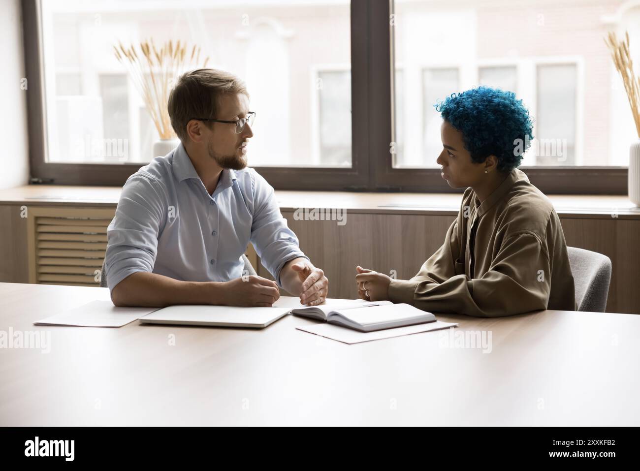 Two multiracial colleagues engaged in serious discussion at conference ...