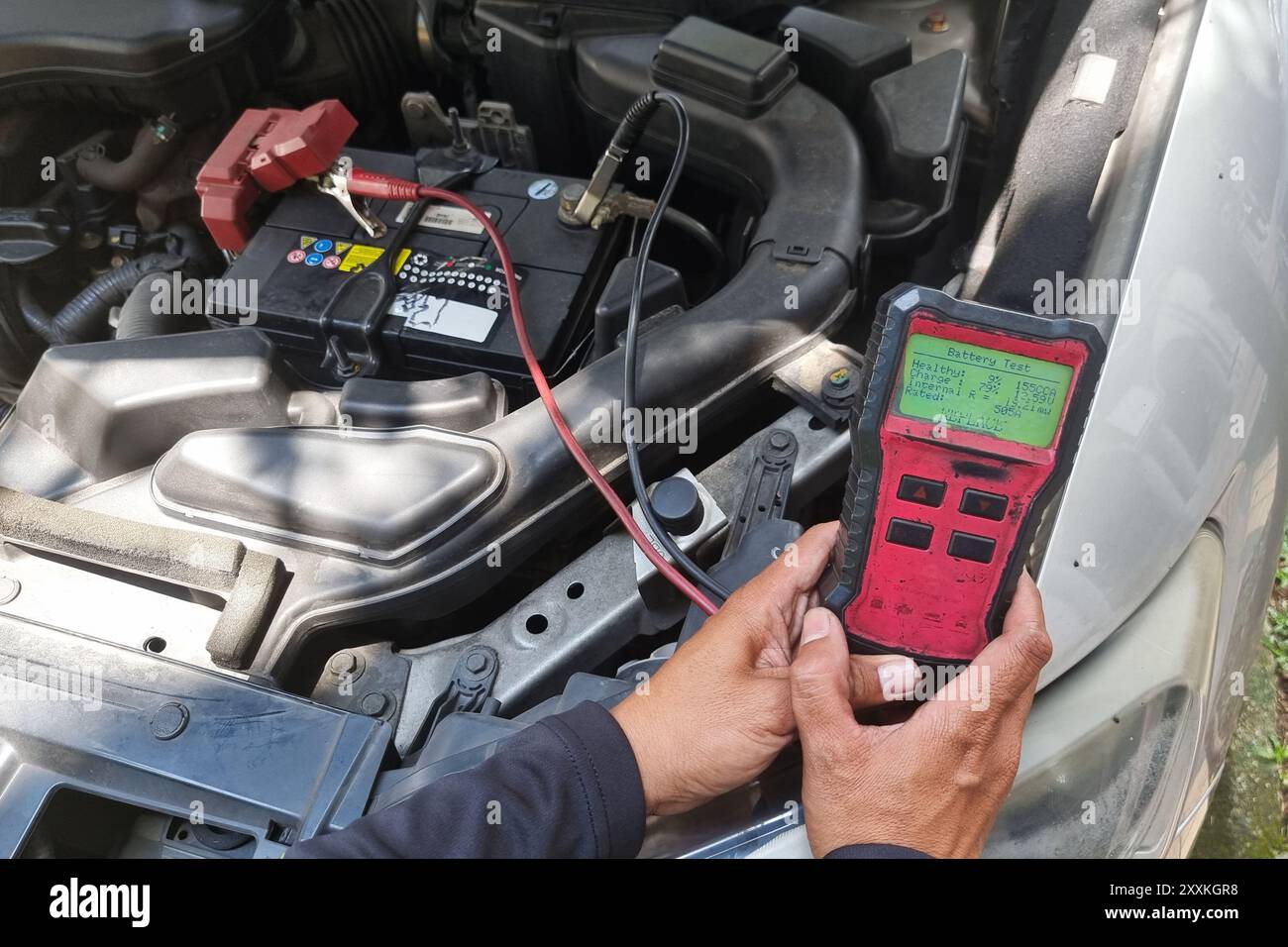 Technician diagnosing old battery health of automobile with instrument ...