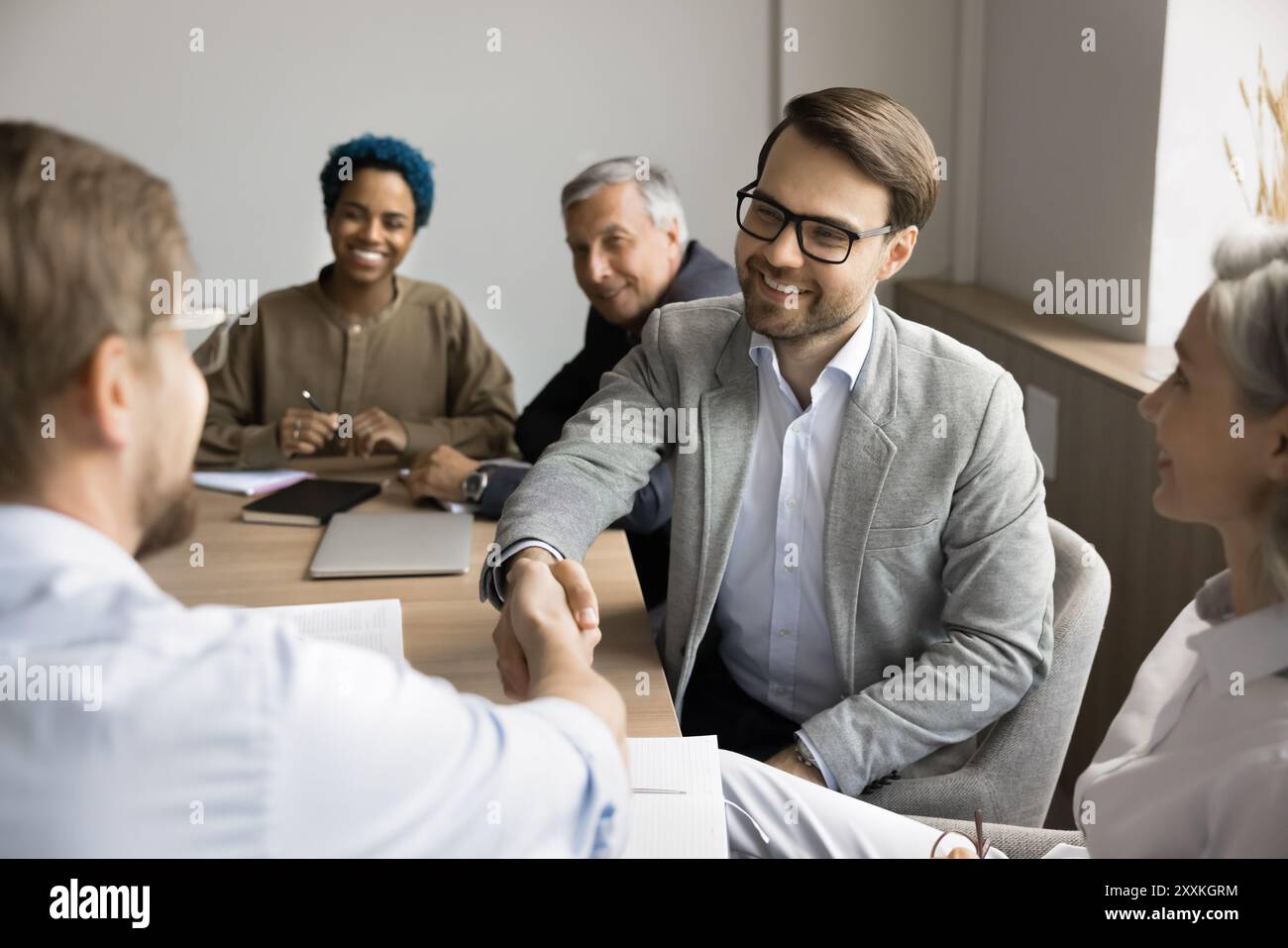 Business partners shaking hands seated at conference table Stock Photo ...