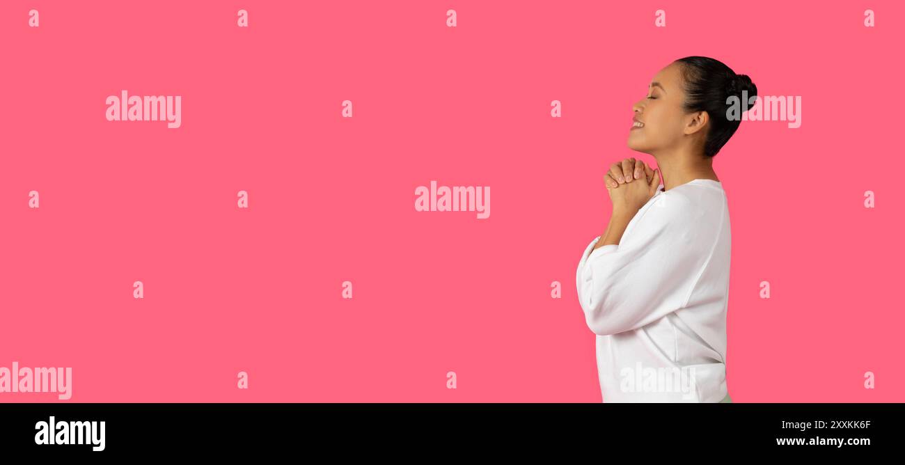 Woman praying thoughtfully against a vibrant pink background Stock ...