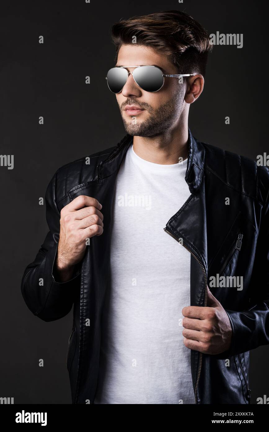 Cool and trendy. Handsome young man adjusting his leather jacket and ...