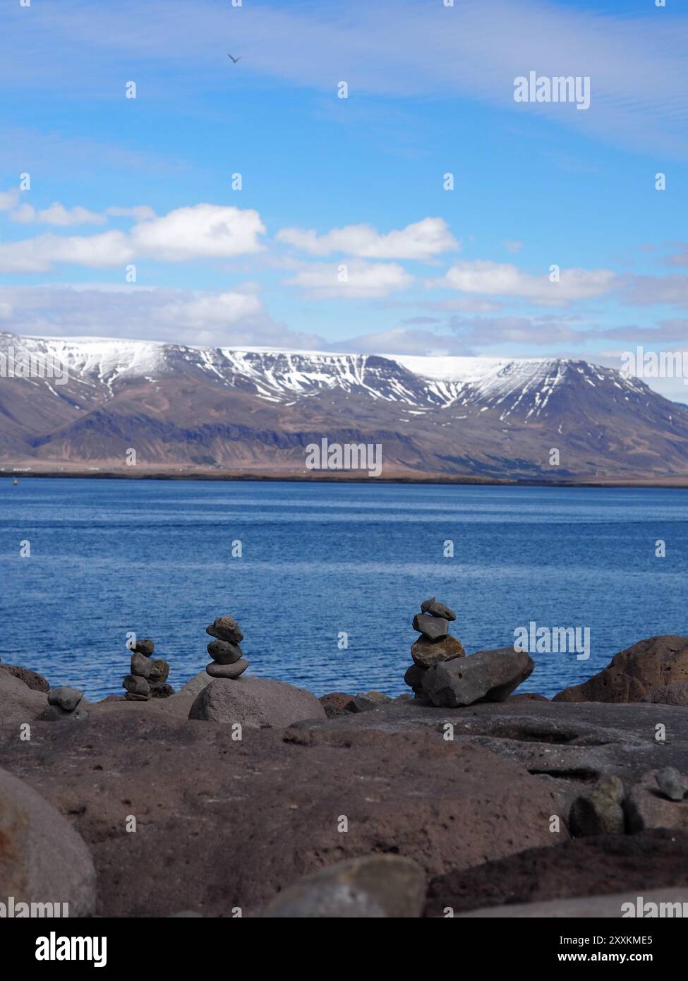 Several neatly stacked rocks by the waterfront, framing a background of ...