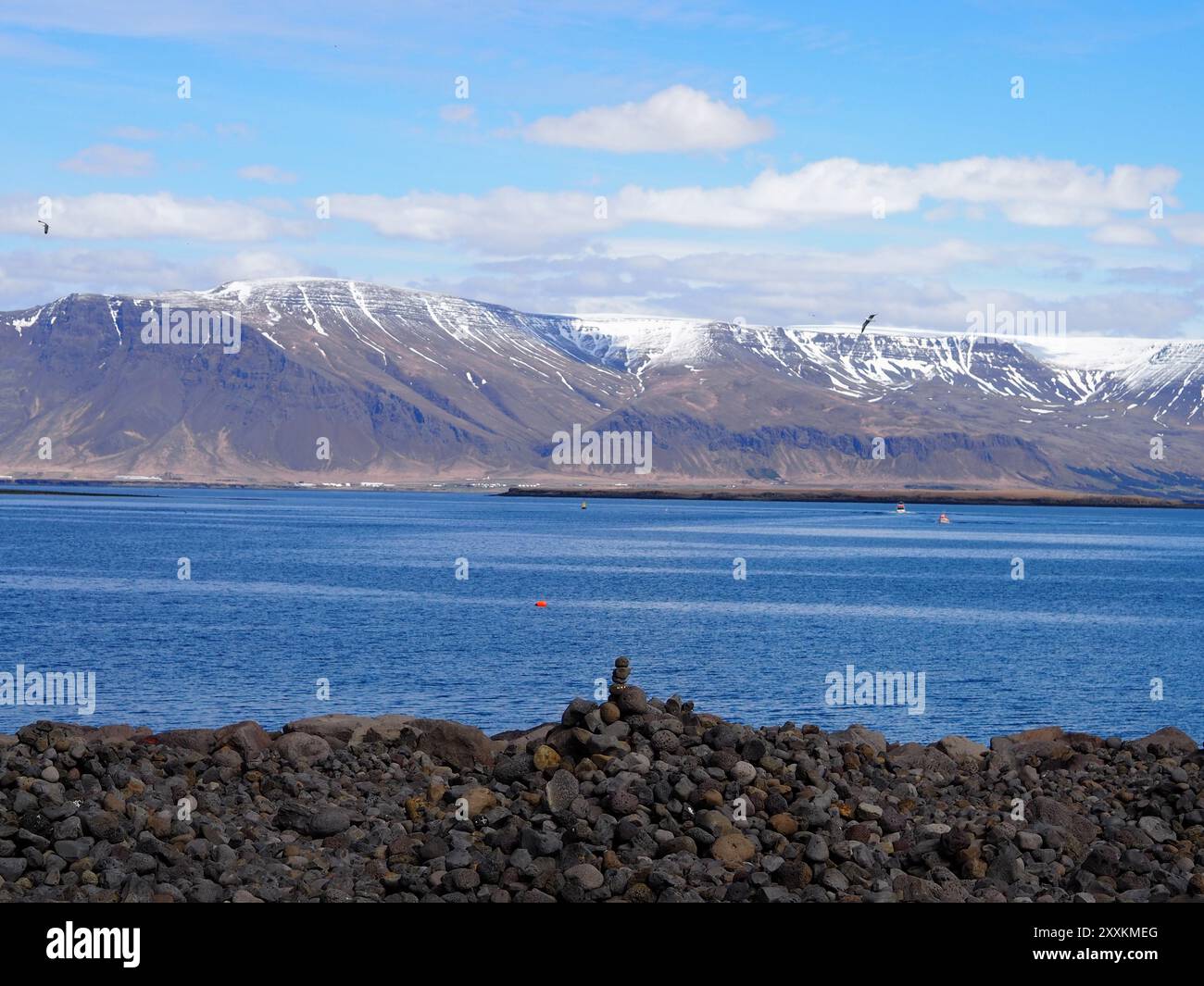 Coastal scenery featuring a rocky shoreline leading to a calm expansive ...