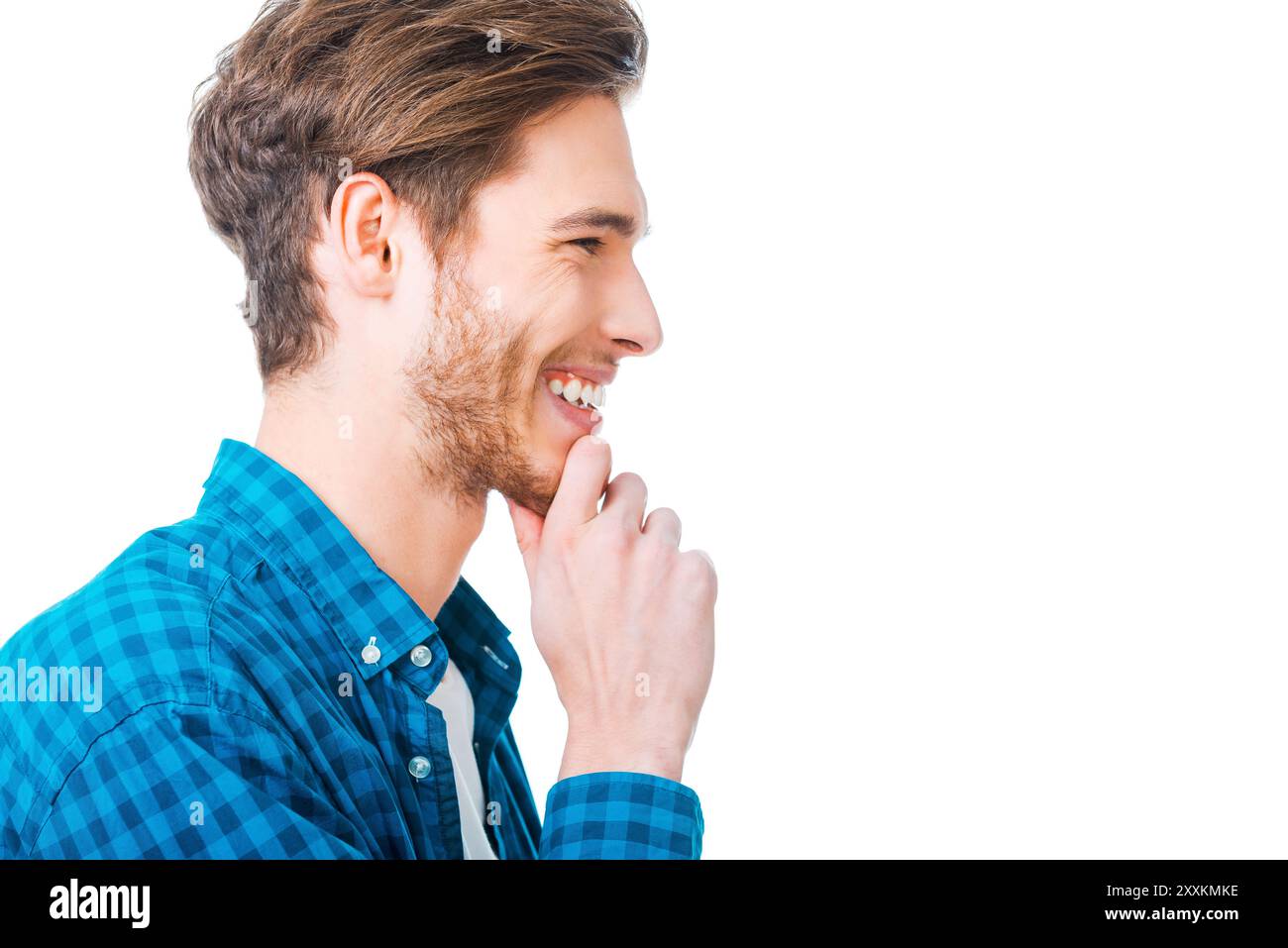 Candid smile. Side view of young man holding hand on chin and smiling ...