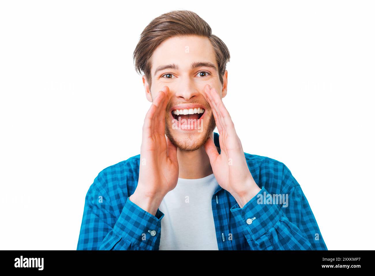 Great news! Cheerful young man holding hands near mouth and shouting ...
