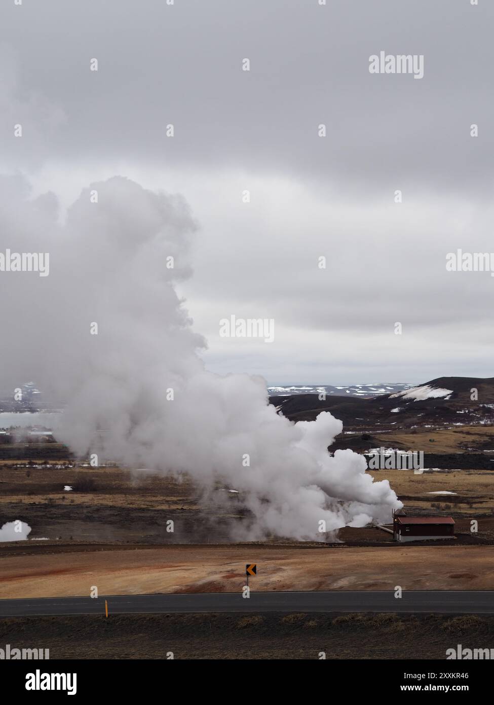 Clouds of steam ascending from a geothermal plant amidst a rugged ...