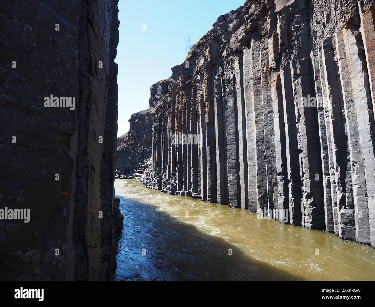 A Scenic River Flows Through A Dramatic Gorge Framed By Tall Natural Basalt Columns