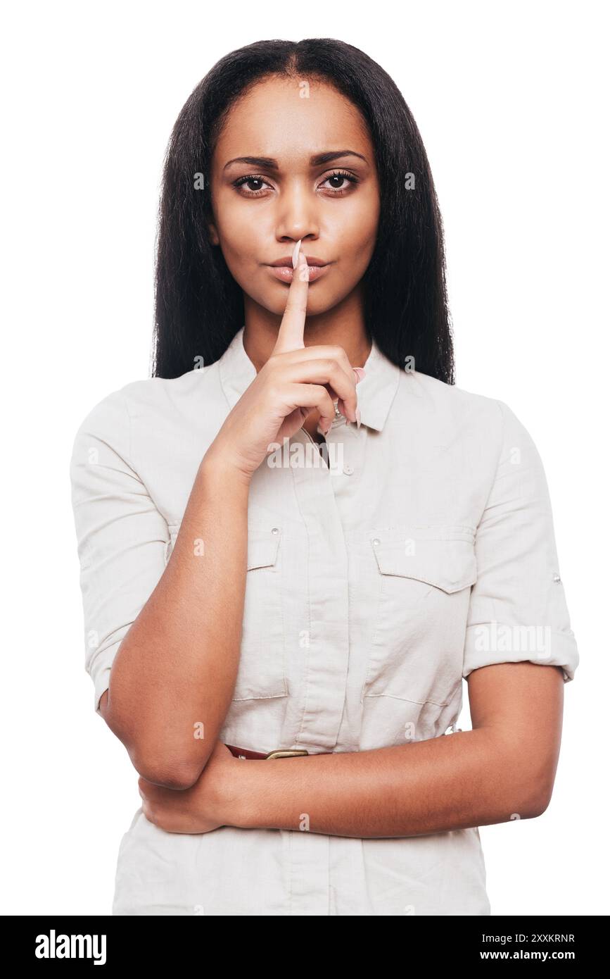 Keep silence! Confident young African woman holding finger on lips ...