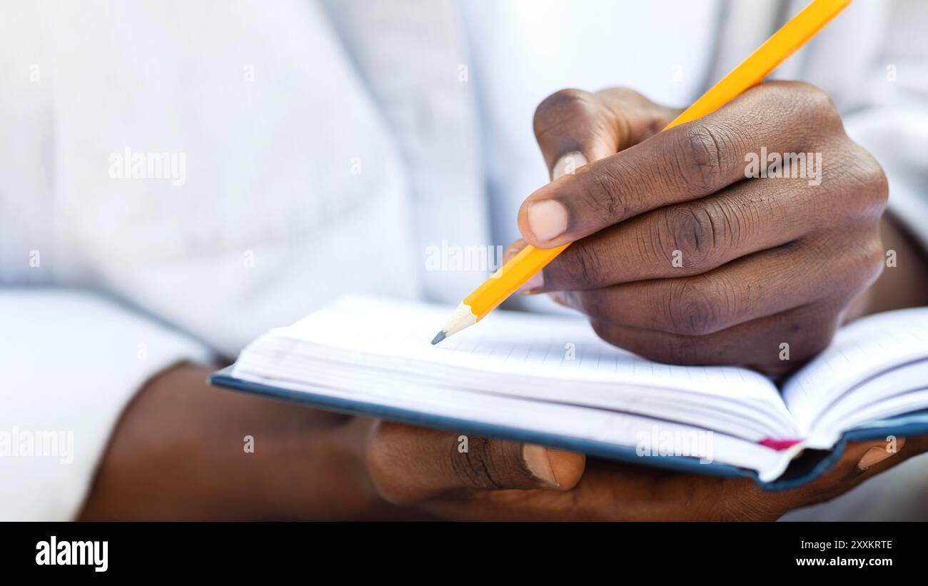 Close up of afro student taking notes, using notepad and pencil Stock ...