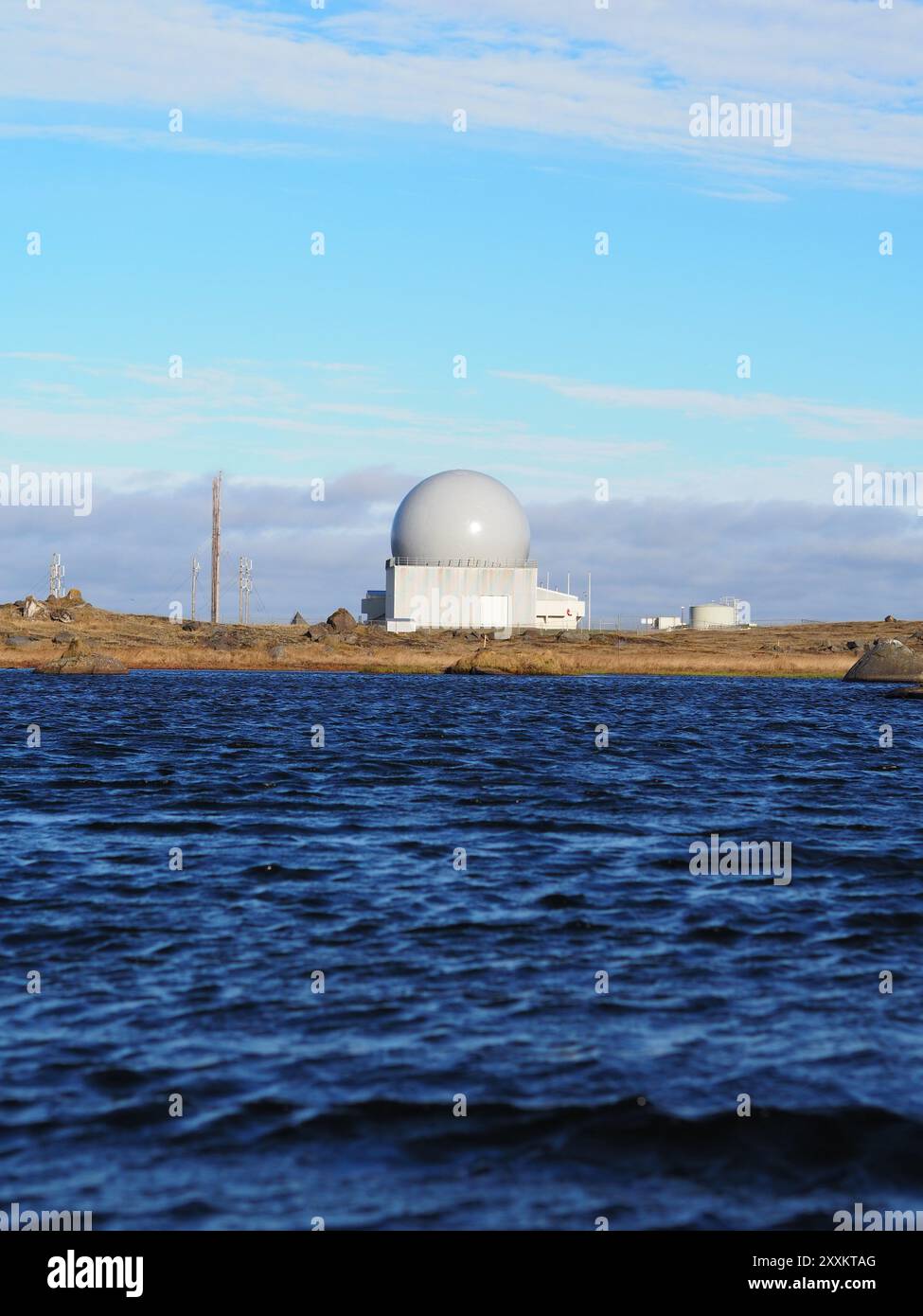 A large geodesic dome structure stands near the water under a clear ...
