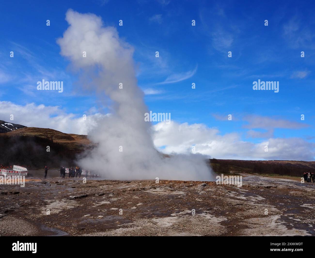 Tourists witness the awe-inspiring eruption of a geyser against the ...