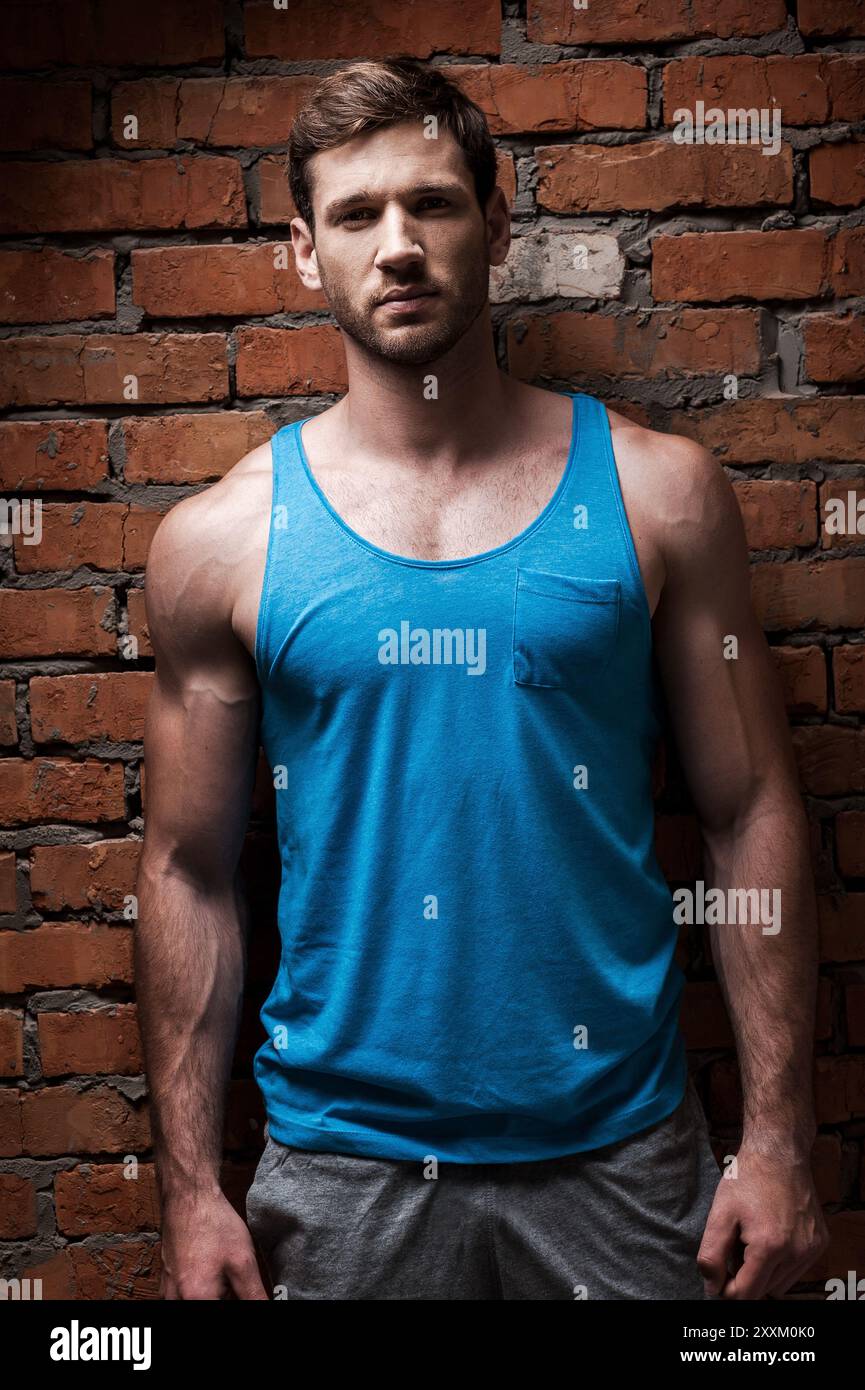 Fit and confident. Confident young muscular man posing while standing ...