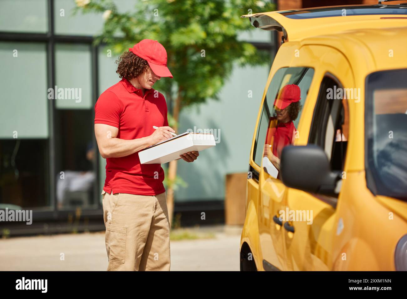 Delivery man in red uniform delivering package while standing next to ...