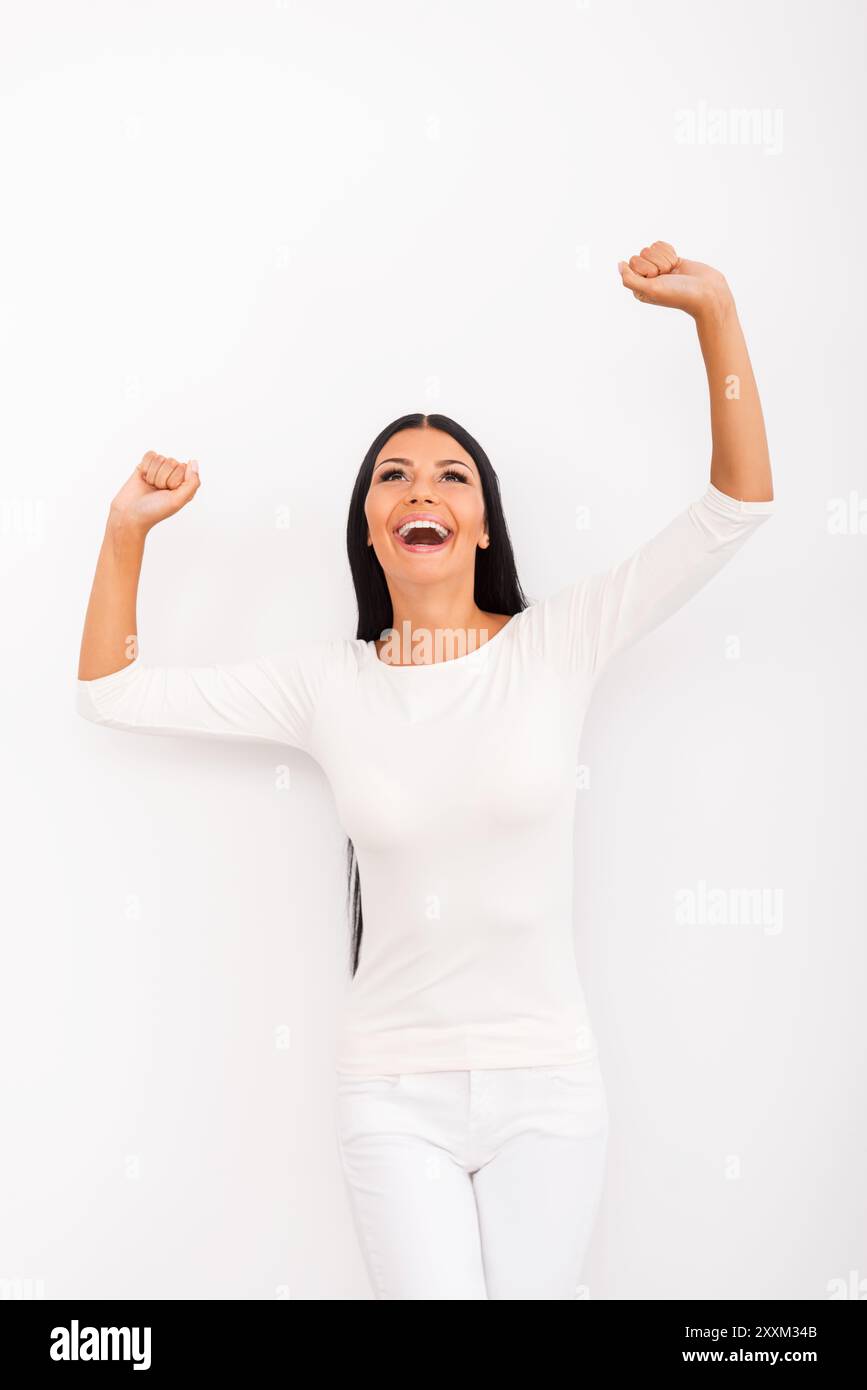 What a lucky day! Happy young woman keeping arms raised while standing ...
