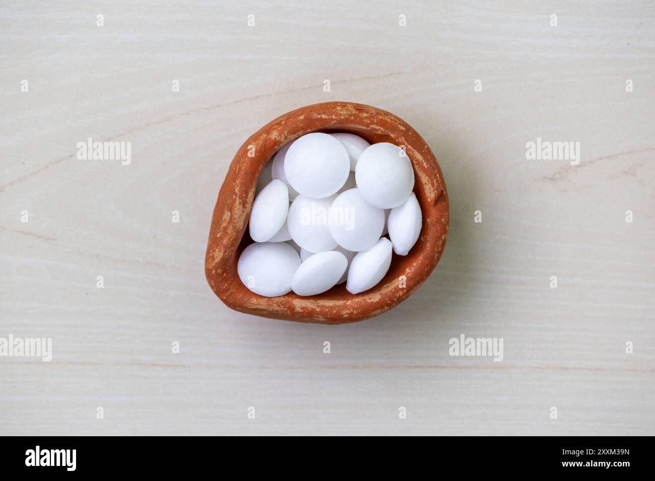 An earthen pot full of white naphthalene balls on wooden background ...