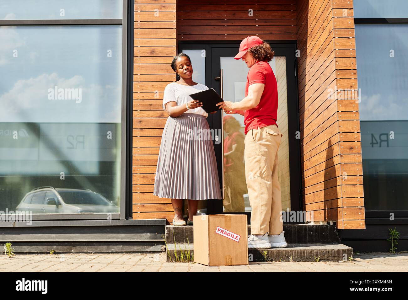 Delivery professional handing fragile package to customer outside ...