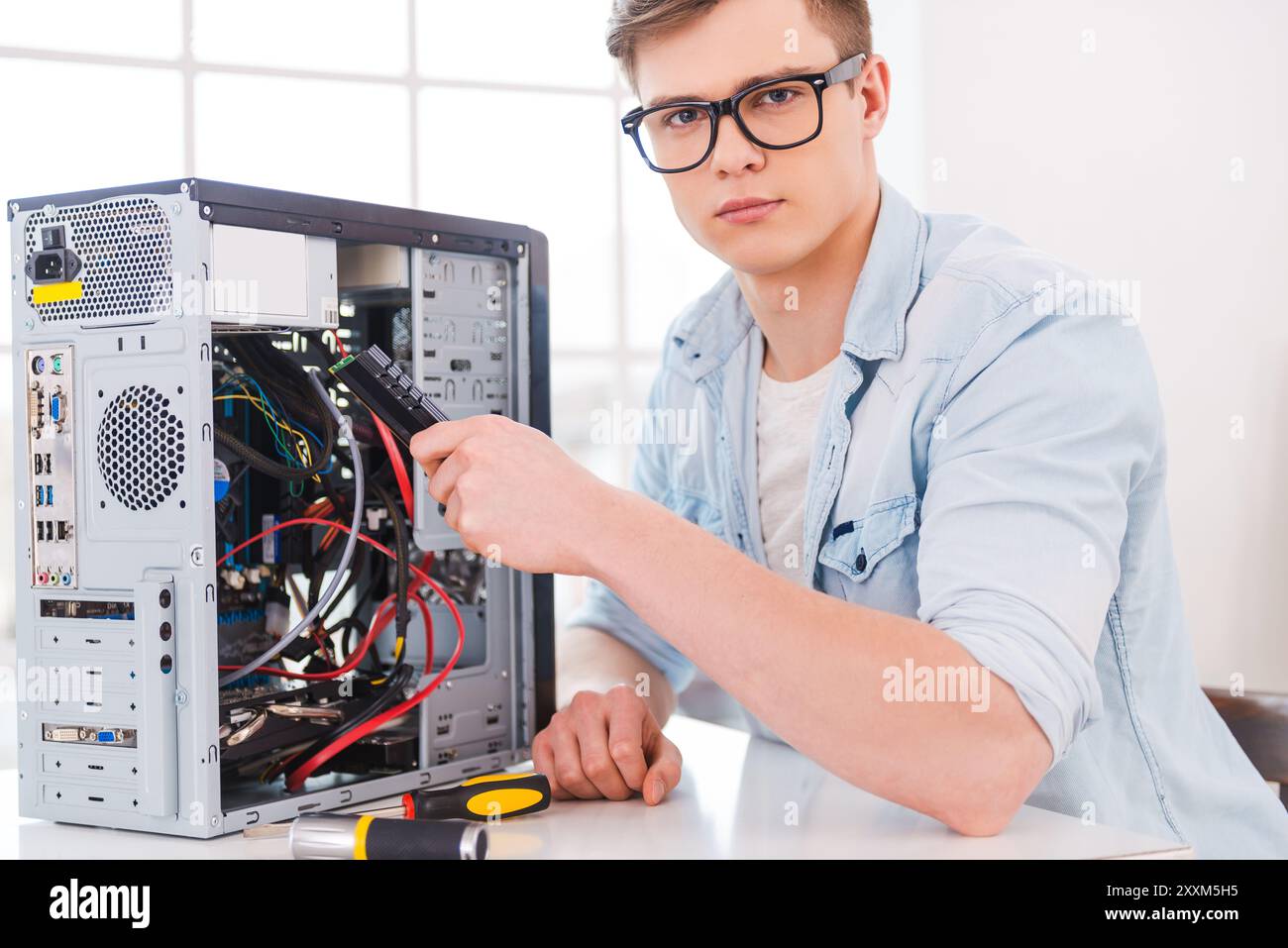 Master of computers. Portrait of handsome young man repairing computer ...