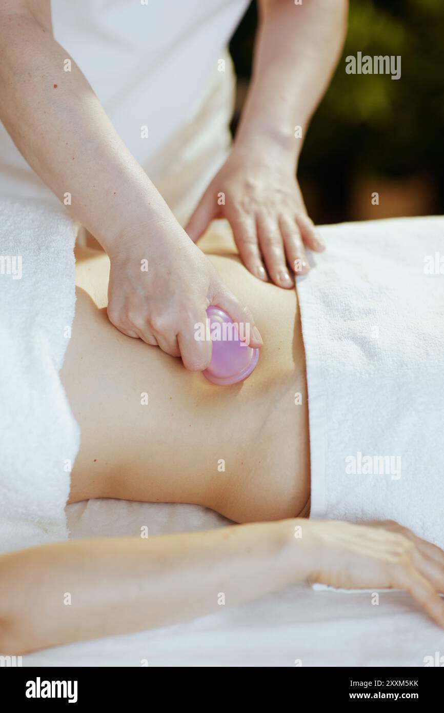 Healthcare time. Closeup on medical massage therapist in spa salon with vacuum therapy cup ...