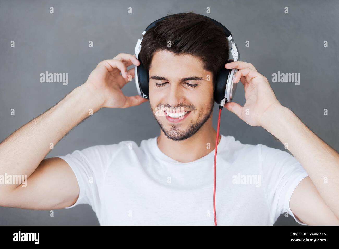 Enjoying his favorite music. Handsome young man keeping eyes closed and ...