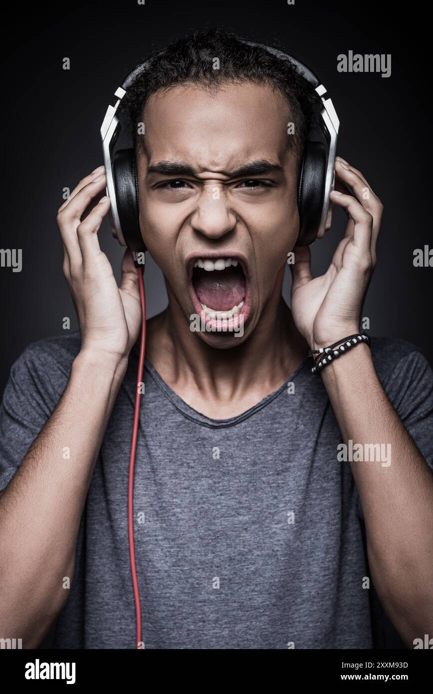 Energy inside me! Furious young African man adjusting headphones and ...