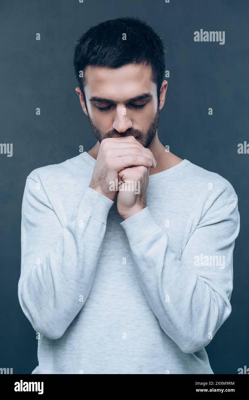 Begging for... Studio shot of handsome young man praying while holding ...