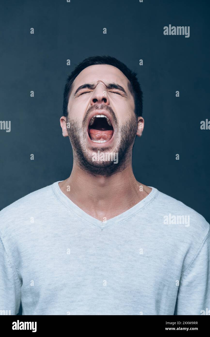 Man shouting. Furious young man keeping eyes closed and mouth open ...