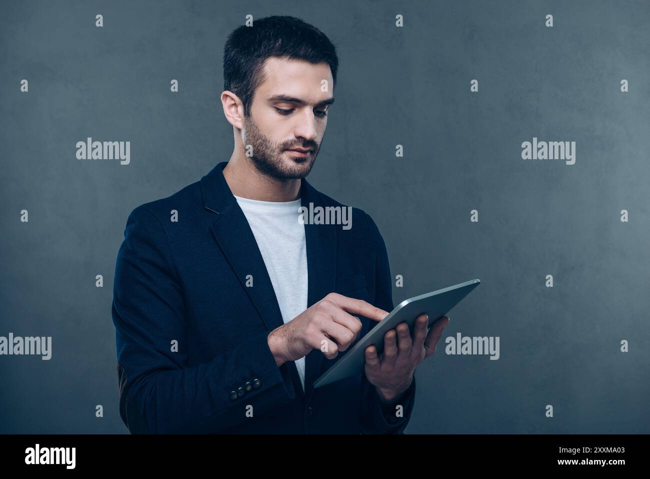Have some work to do. Handsome young man working on his digital tablet ...