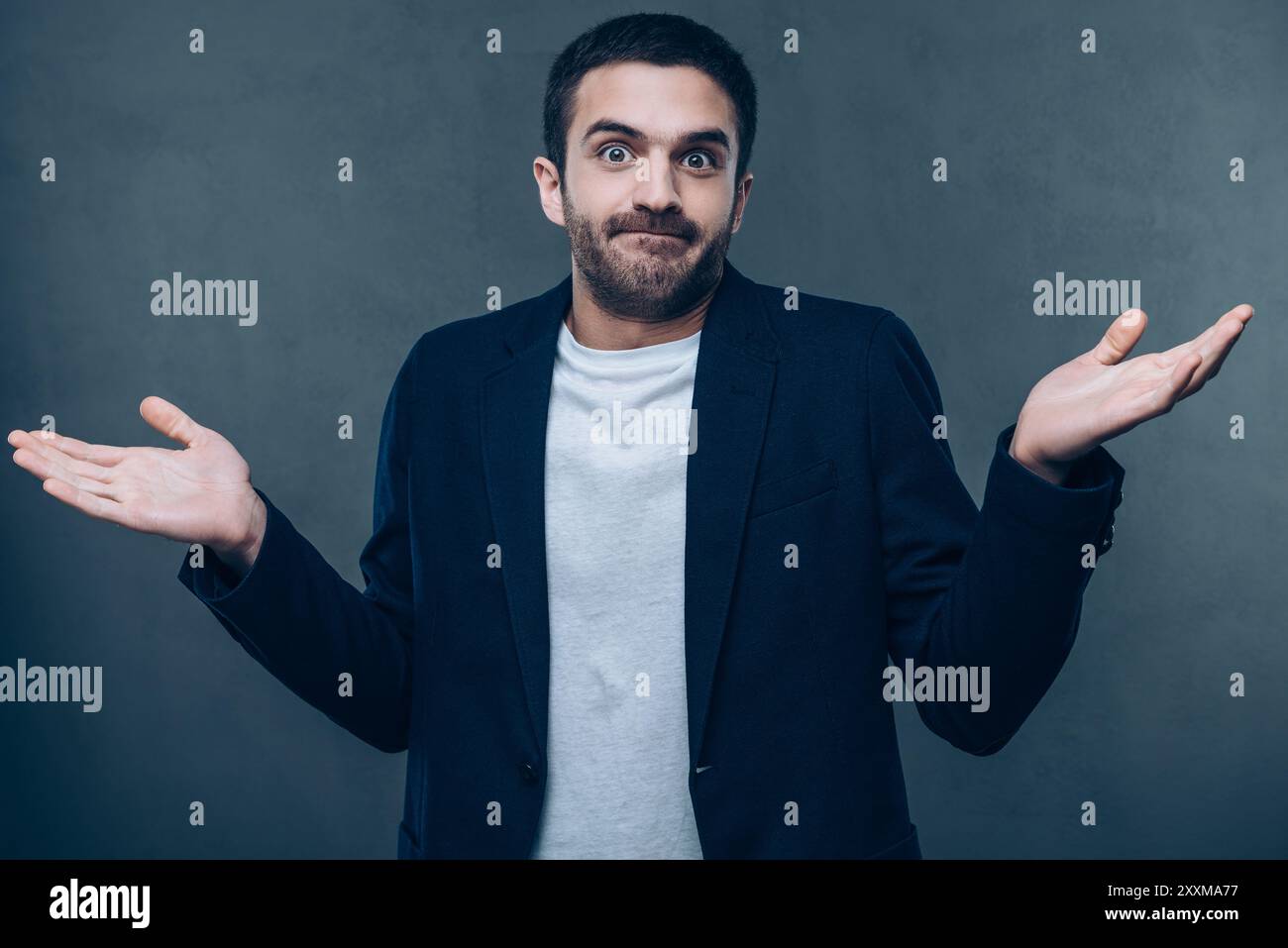 Who knows? Confused young man stretching out his arms and grimacing ...
