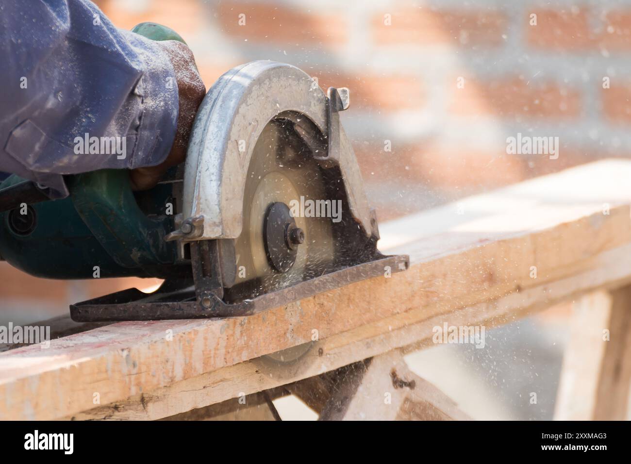 Carpenter using circular saw with a rapidly rotating toothed disk in ...