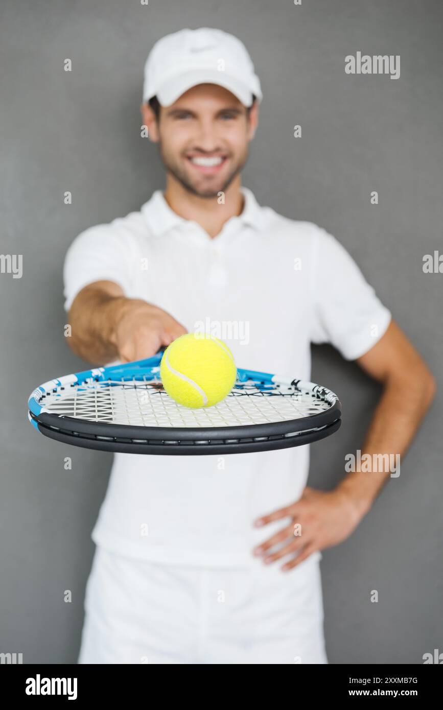 Play with me! Happy young man in sports clothes stretching out tennis ...