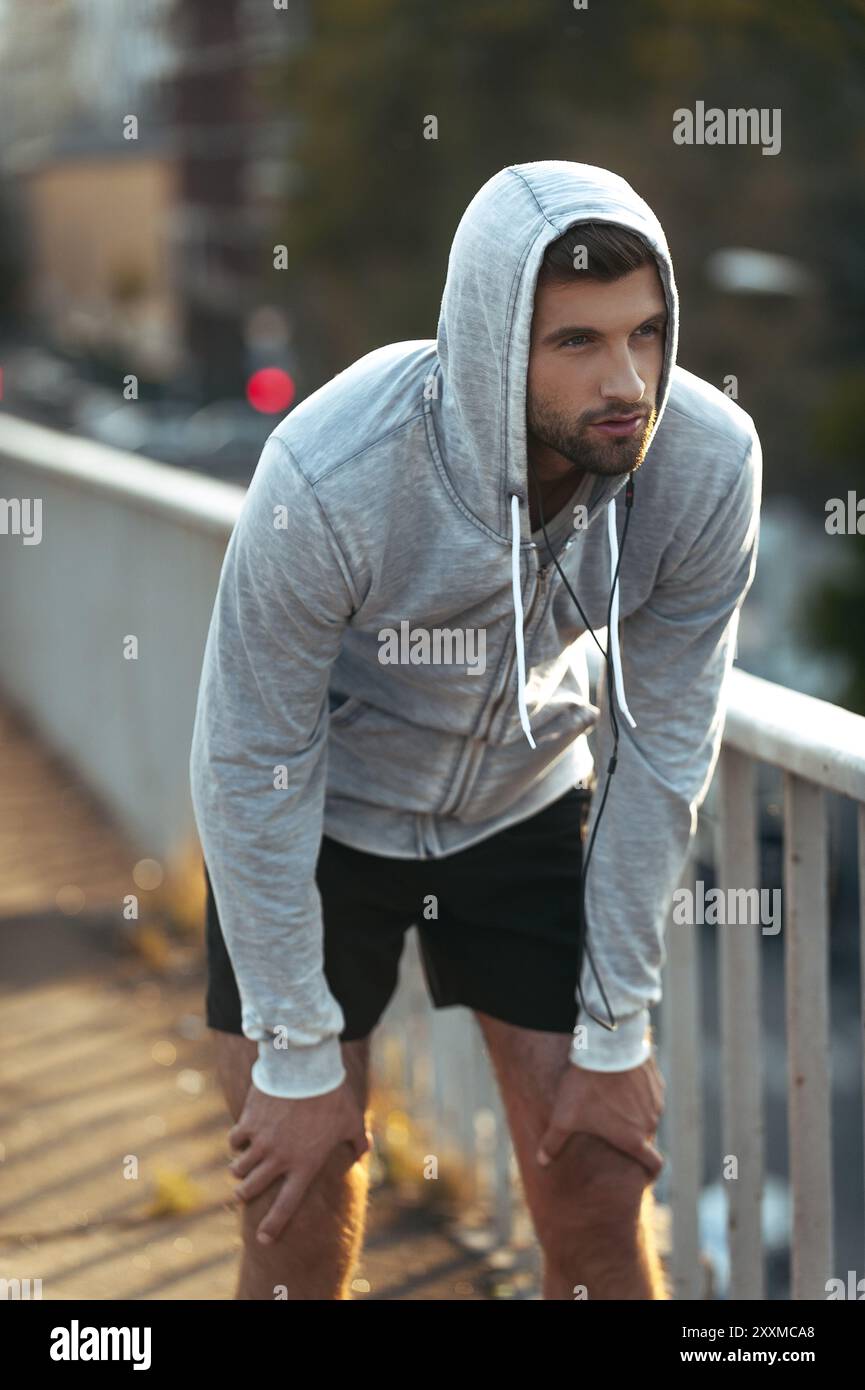 Breathe deep and keep on running. Tired young man resting after running ...