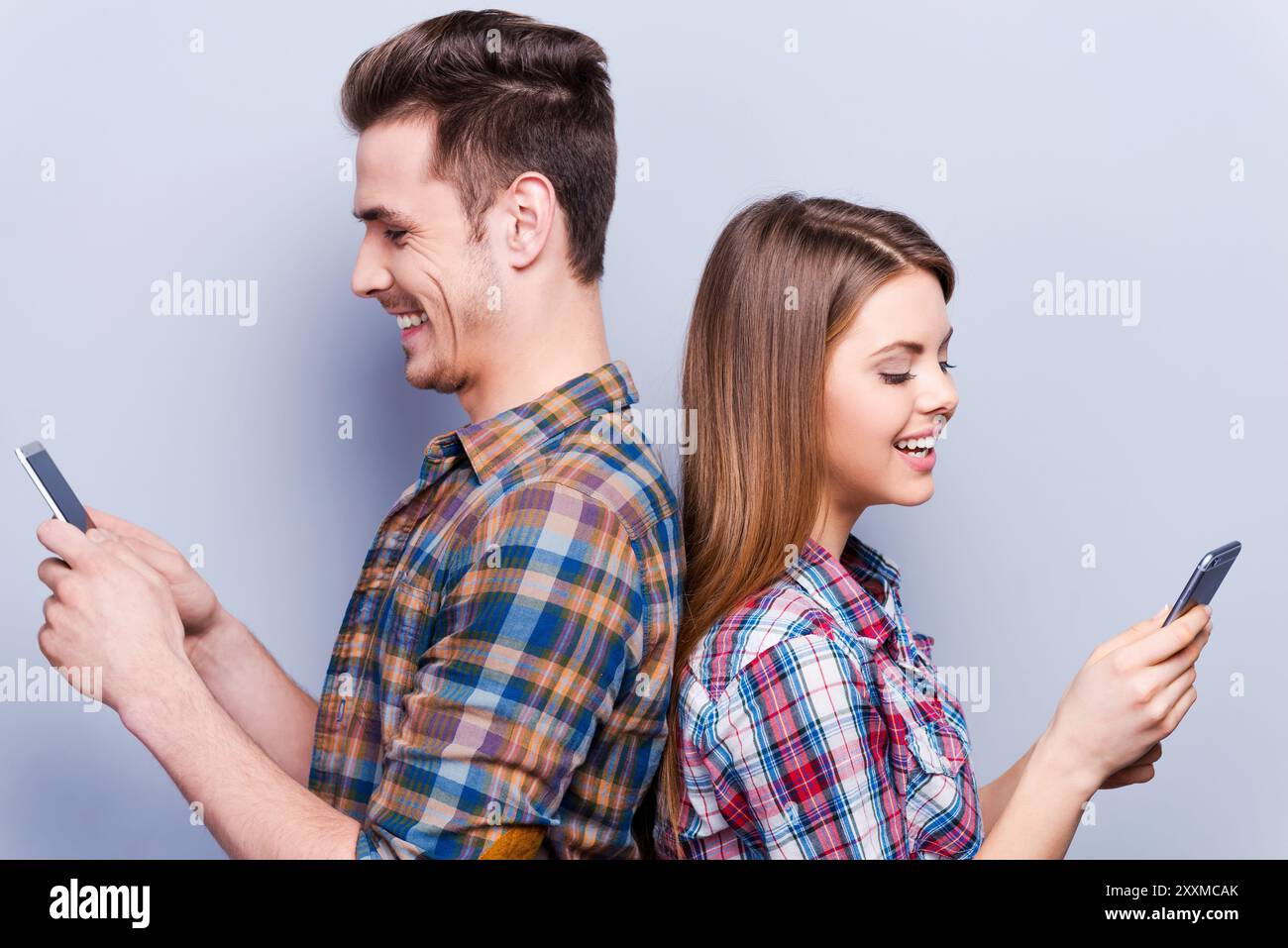 Romantic messages. Beautiful young loving couple holding mobile phones ...