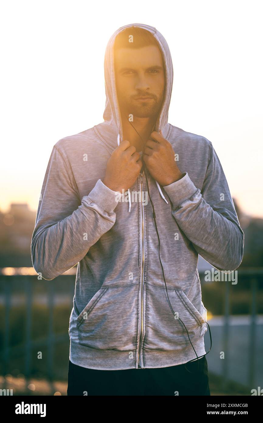 Used to win. Handsome young man adjusting his hood and looking at ...