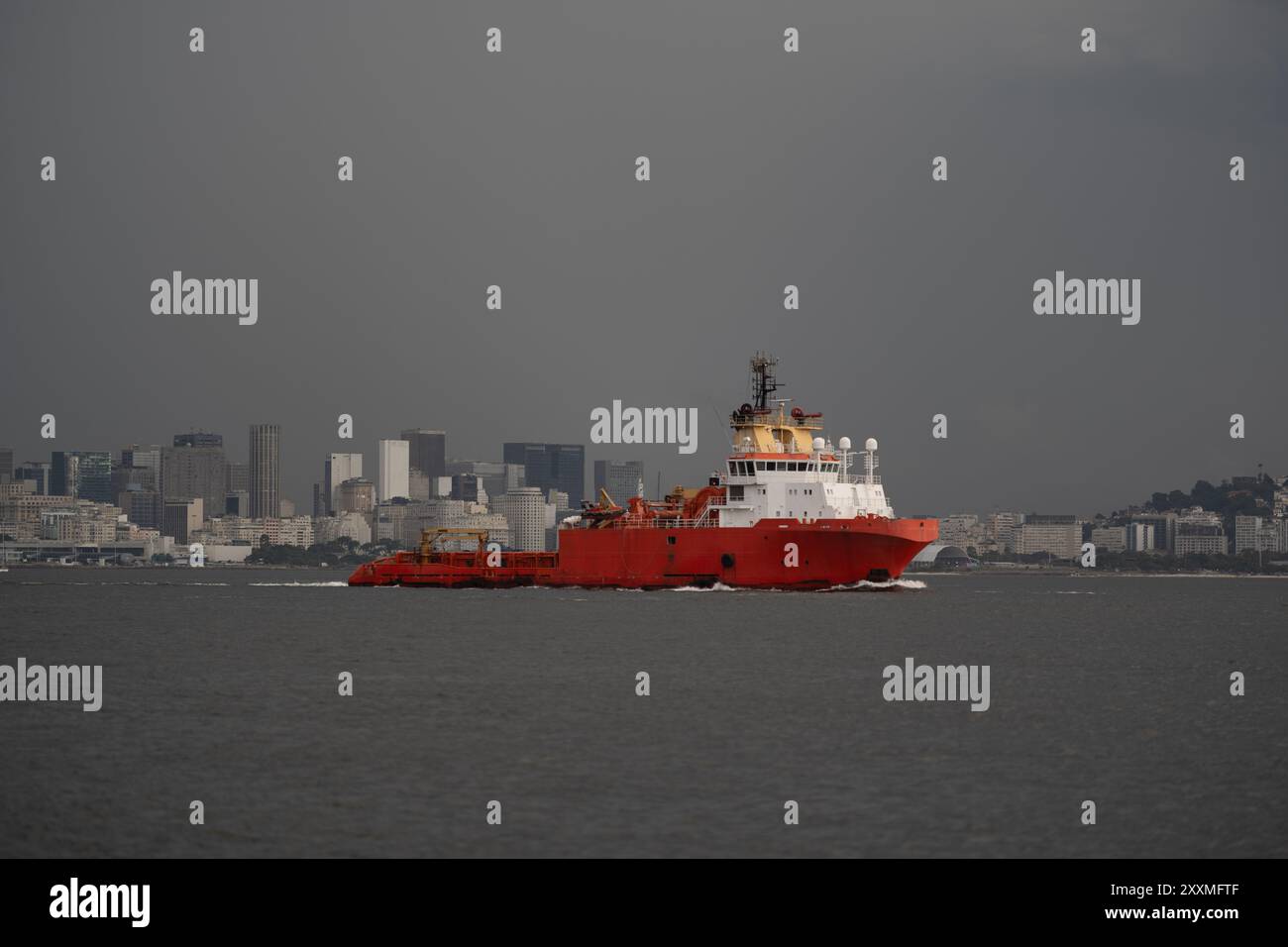 A bright red offshore supply vessel (OSV) navigates the calm waters ...