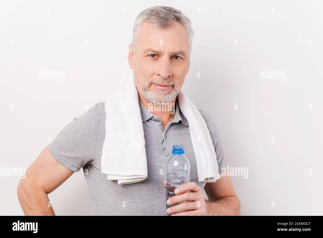 Staying hydrated. Confident grey hair senior man carrying towel on ...