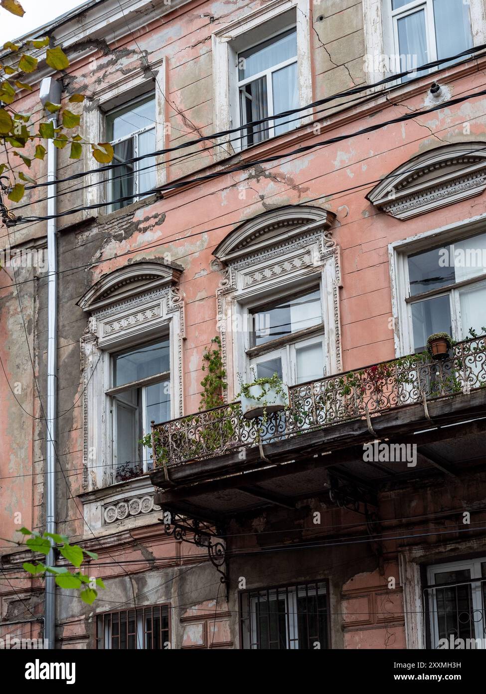pink facade of old apartment house with openwork metal balcony railing in center of Tbilisi city ...