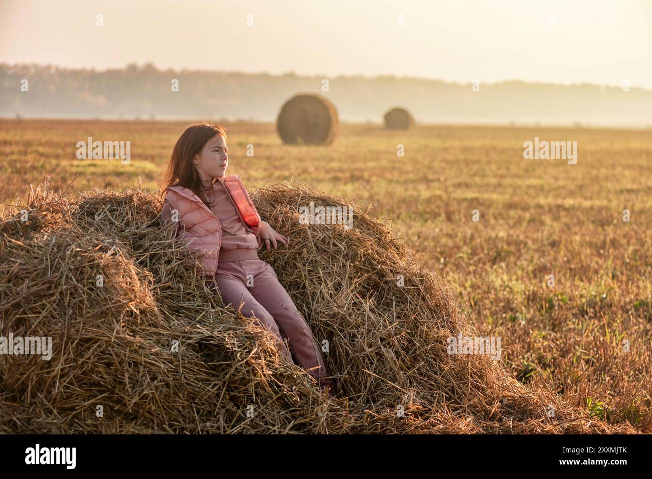Cute teenage girl in field with wheat clippings and haystacks. morning, fog Stock Photo - Alamy